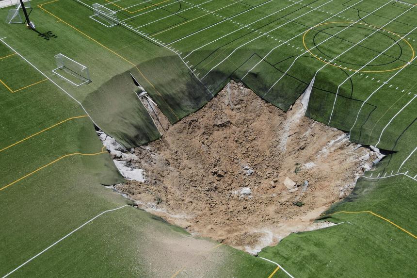 Sinkhole ‘at least 30m wide’ swallows tall light pole, damages football ...